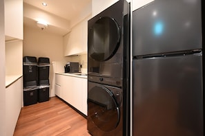 Cozinha compacta com geladeira de aço inoxidável, forno embutido e lava-louças.
