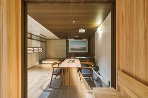 Uma sala de reuniões moderna com uma mesa comprida, cadeiras e uma tela de projetor exibindo 'essential' na parede.