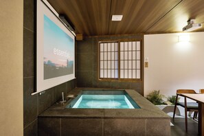 Quarto com uma pequena piscina, tela de projetor exibindo a palavra 'essential' e uma porta japonesa tradicional deslizante.