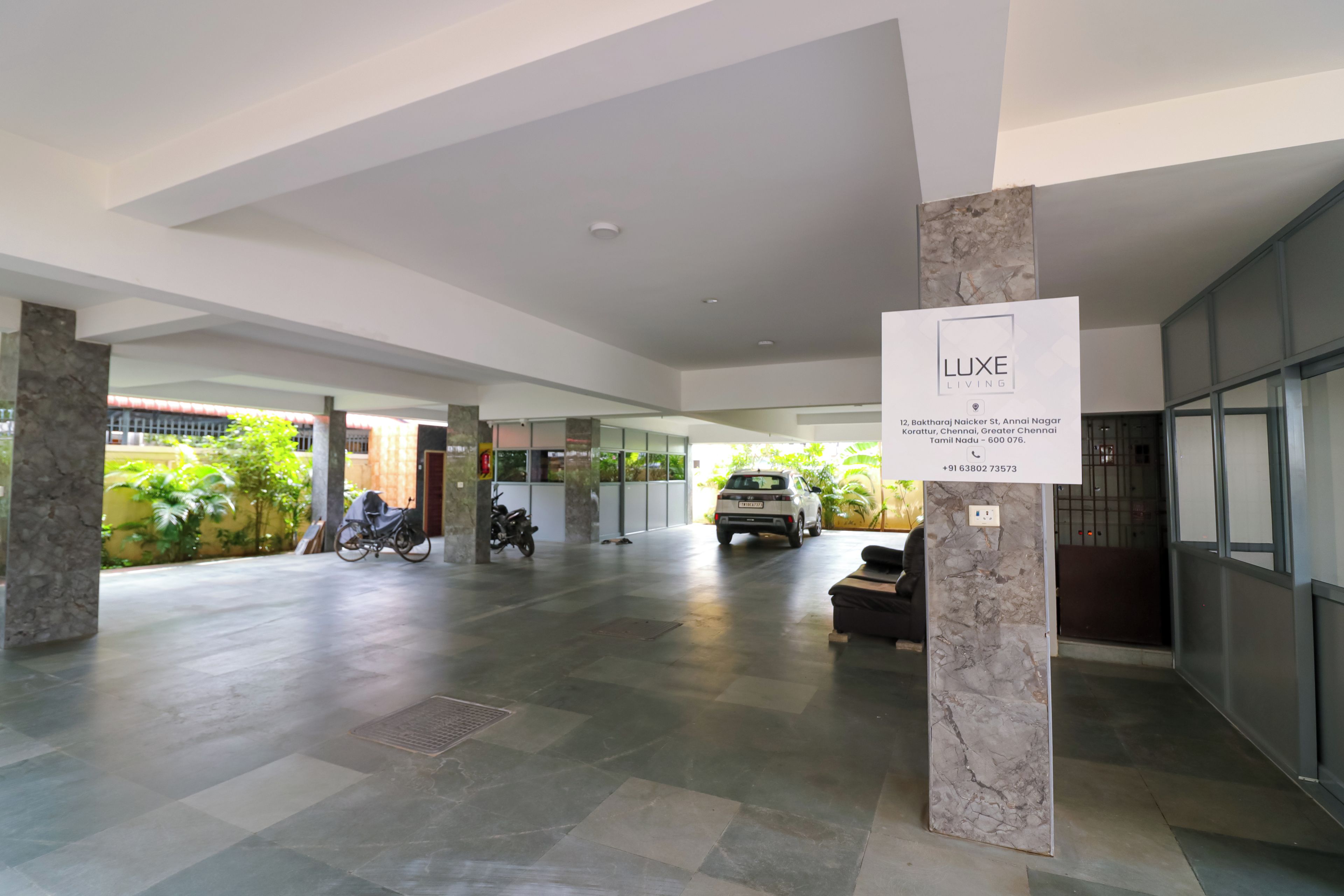 Um lobby espaçoso com uma placa indicando LUXE LIVING, um carro e uma motocicleta.