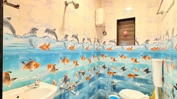 Casa de banho com um mural de golfinhos e peixes, uma pia, sanita e um balde.