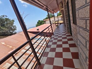 Uma varanda com piso xadrez, grades de metal e vista da região ao redor.