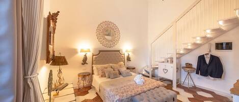 Quarto com cama, mesas de cabeceira, espelho, lustre, cômoda e cabideiro.