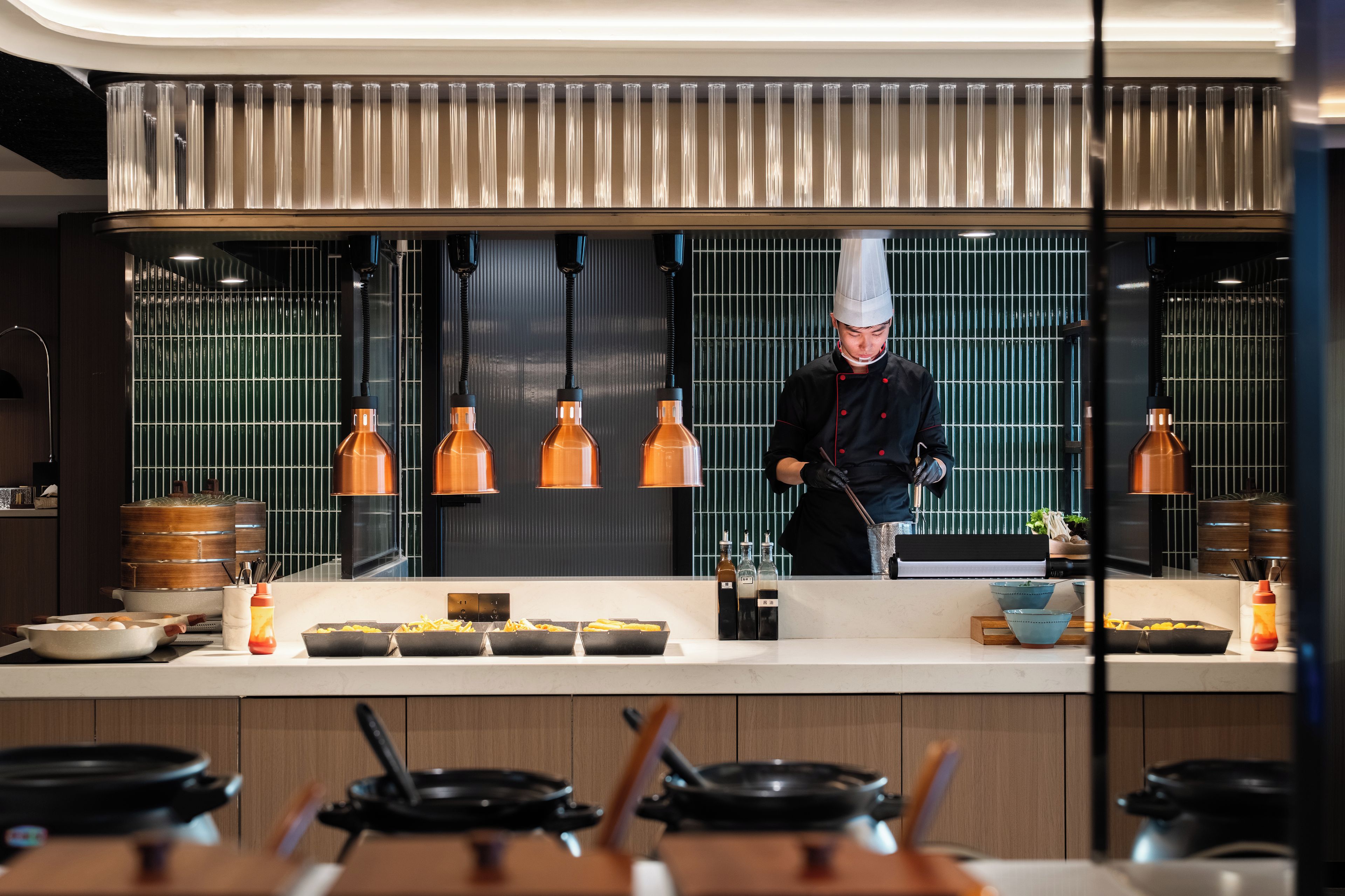 Cozinha moderna com eletrodomésticos de aço inoxidável, um chef trabalhando e um layout limpo e organizado.