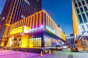Um edifício moderno com letreiros iluminados, grandes janelas e entrada imponente.
