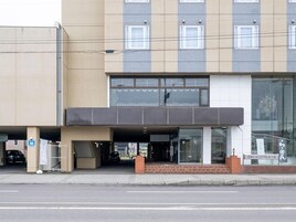 Um edifício moderno com entrada coberta, janelas amplas e uma escadaria visível.