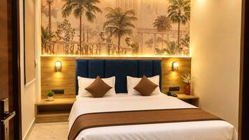 Quarto de hotel com cama, mesas de cabeceira, ventilador de teto e um mural na parede.