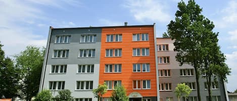 Um edifício residencial de vários andares com fachada plana, janelas uniformemente espaçadas e entrada central.