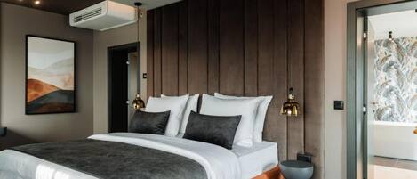 Quarto moderno com uma cama grande, ar condicionado fixado na parede e porta que dá para uma varanda.