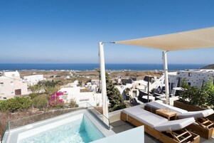 Área de piscina no terraço, com vista para o mar e uma cidade ao fundo.