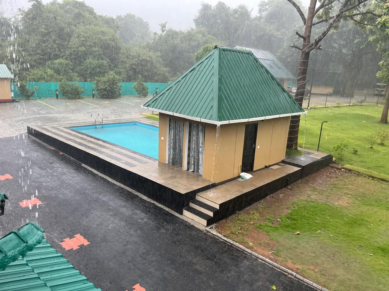 Um pequeno edifício com telhado verde ao lado de uma piscina.