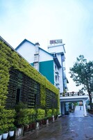 Um hotel com fachada moderna, uma parede verde com plantas e uma placa indicando que é um hotel.