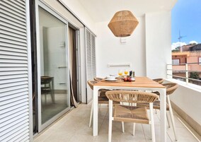 Varanda com mesa e cadeiras, luminária pendente e porta de vidro deslizante para um pátio.