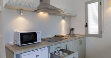 Uma cozinha compacta com micro-ondas, torradeira e pia.