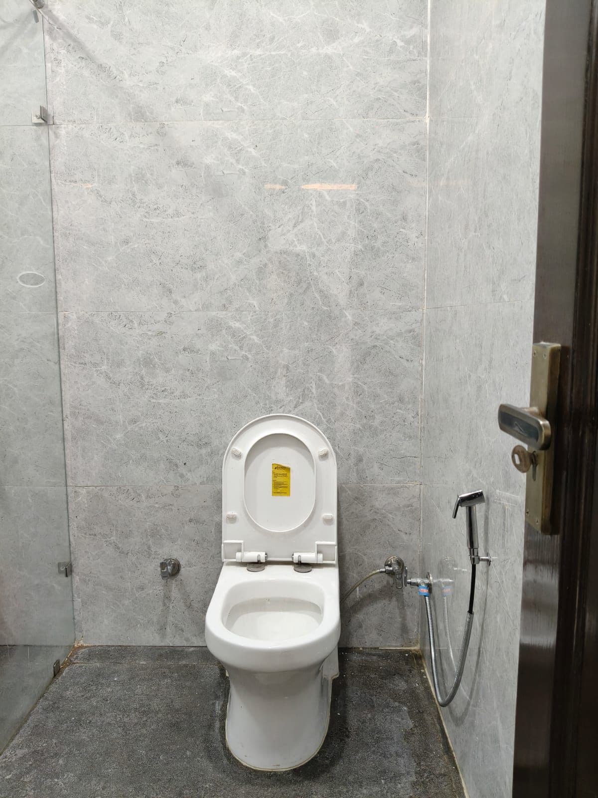 Casa de banho pequena e fechada, com sanita branca, chuveiro e porta com puxador.