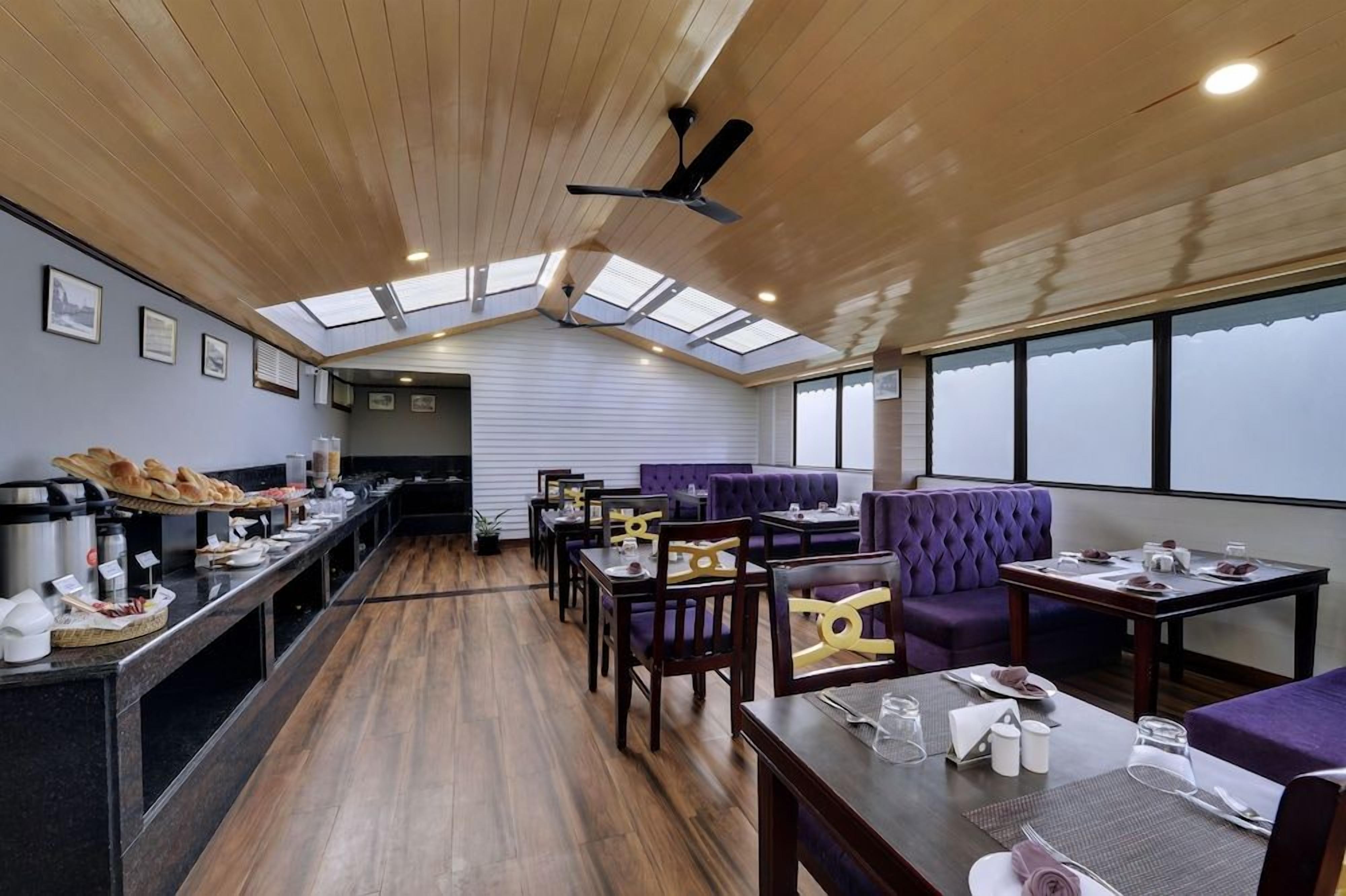 Restaurante com teto alto, claraboias e diversos assentos, incluindo mesas e cabines estofadas.