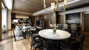 Uma sala de estar moderna com uma mesa redonda de mármore, poltronas de couro preto e uma lareira.