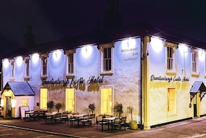 Um edifício com placas indicando 'Dunstanburgh Castle Hotel' e 'Restaurante Bar Salões de Chá'.
