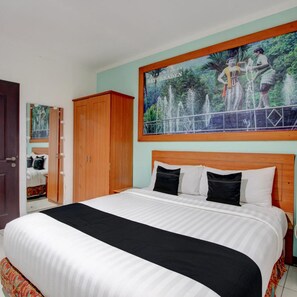 Quarto de hotel com uma cama, um guarda-roupa e um quadro de uma paisagem tropical.
