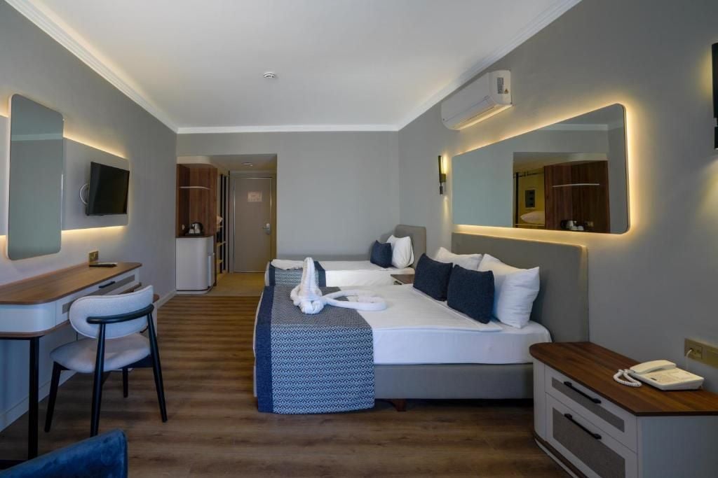 Quarto de hotel com cama, mesa de cabeceira, cadeira, escrivaninha e um espelho grande.
