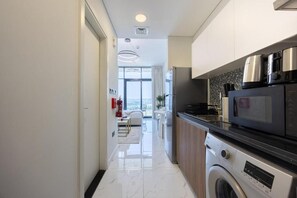 Cozinha moderna com eletrodomésticos de aço inoxidável, máquina de lavar roupa e área de refeições com vista.