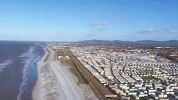 Uma área costeira com praia e vários trailers brancos dispostos em fileiras.