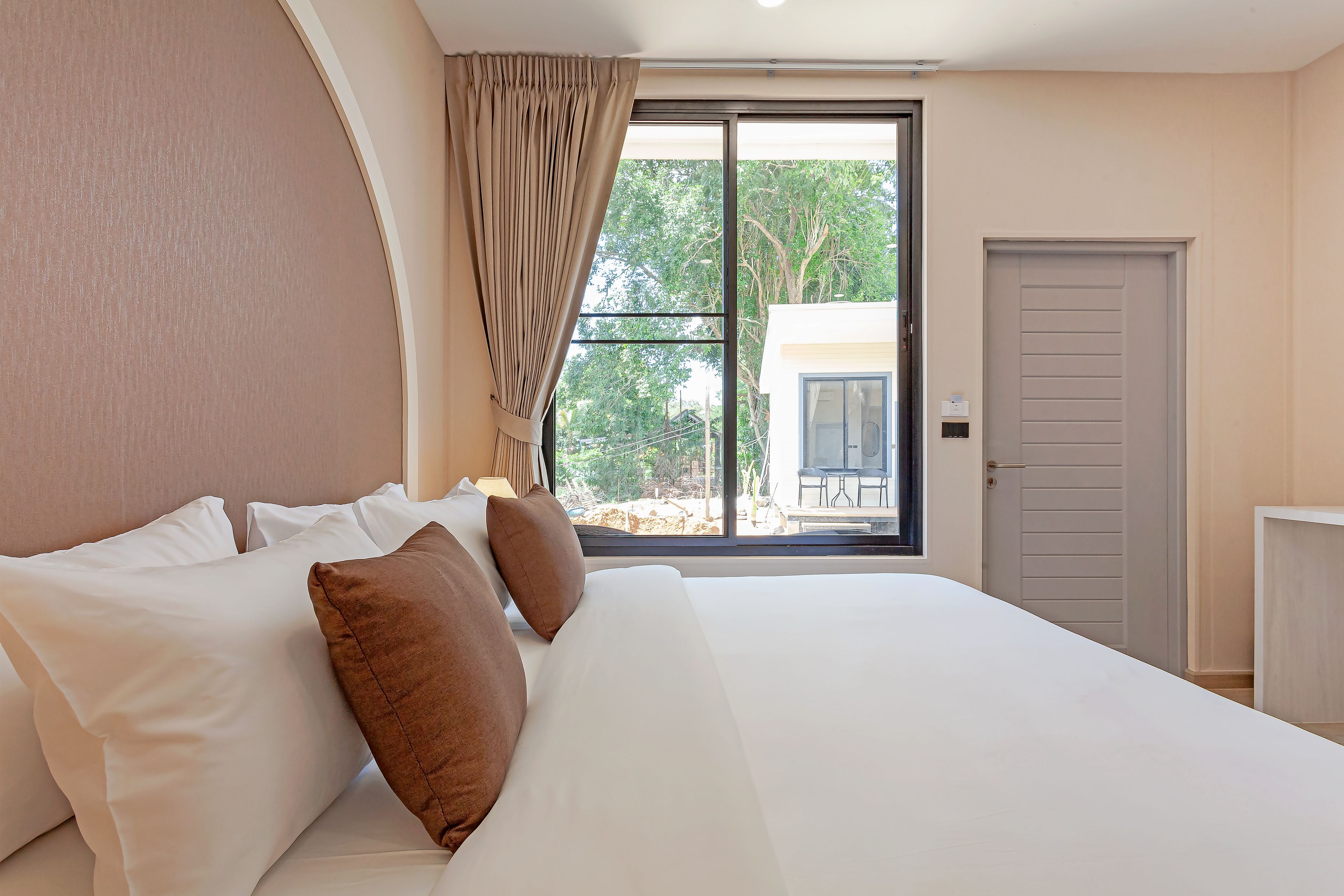 Quarto de hotel com uma cama grande, janela com cortinas e vista para o exterior.