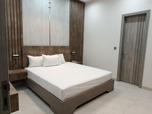 Quarto com uma cama grande, cabeceira de madeira, mesas de cabeceira e um guarda-roupa.