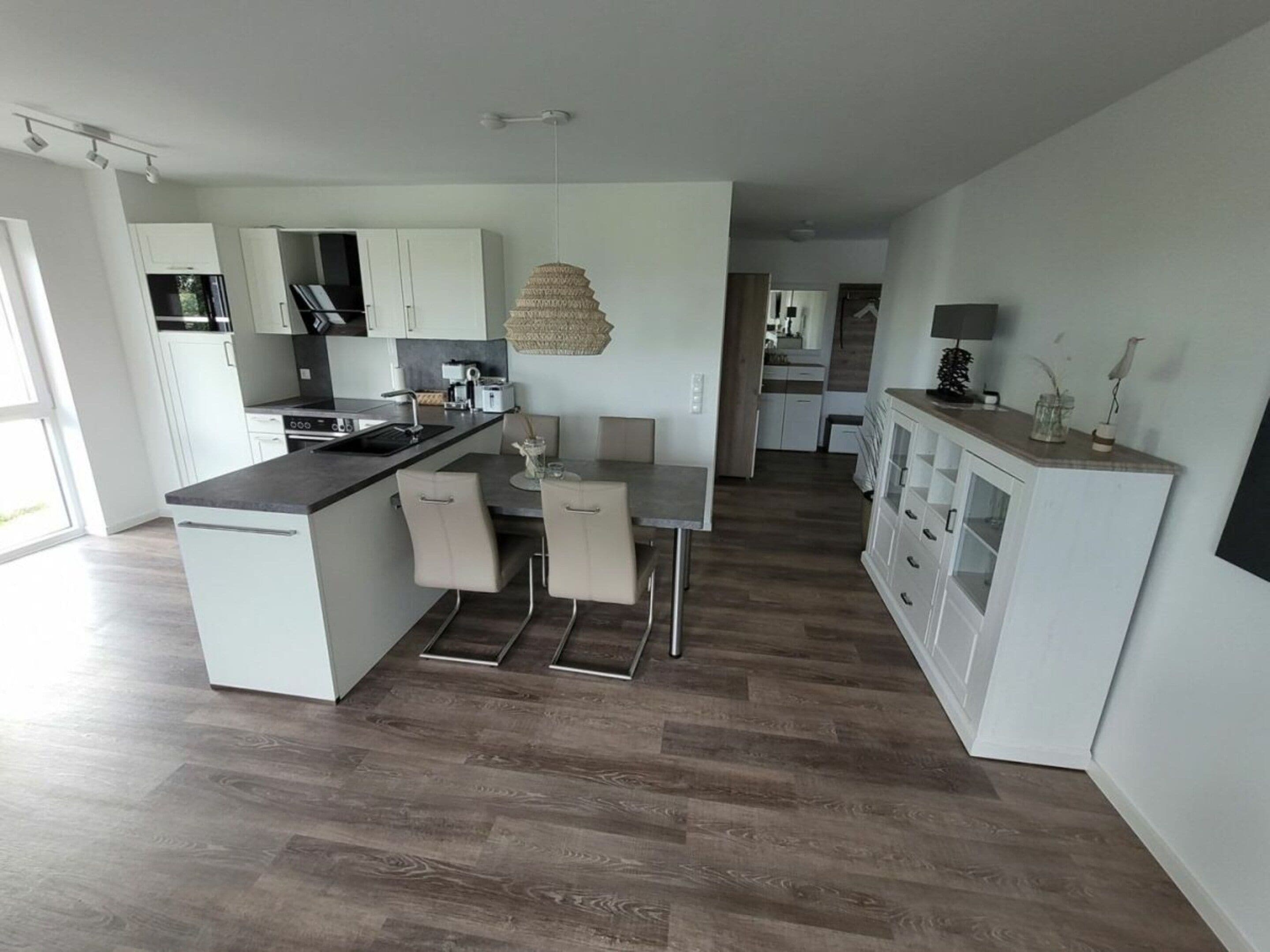 Uma cozinha moderna com ilha central, área de refeições e vista para a sala de estar.