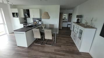 Uma cozinha moderna com ilha central, área de refeições e vista para a sala de estar.