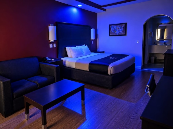 Quarto de hotel moderno com cama, sofá, mesinha e escrivaninha.