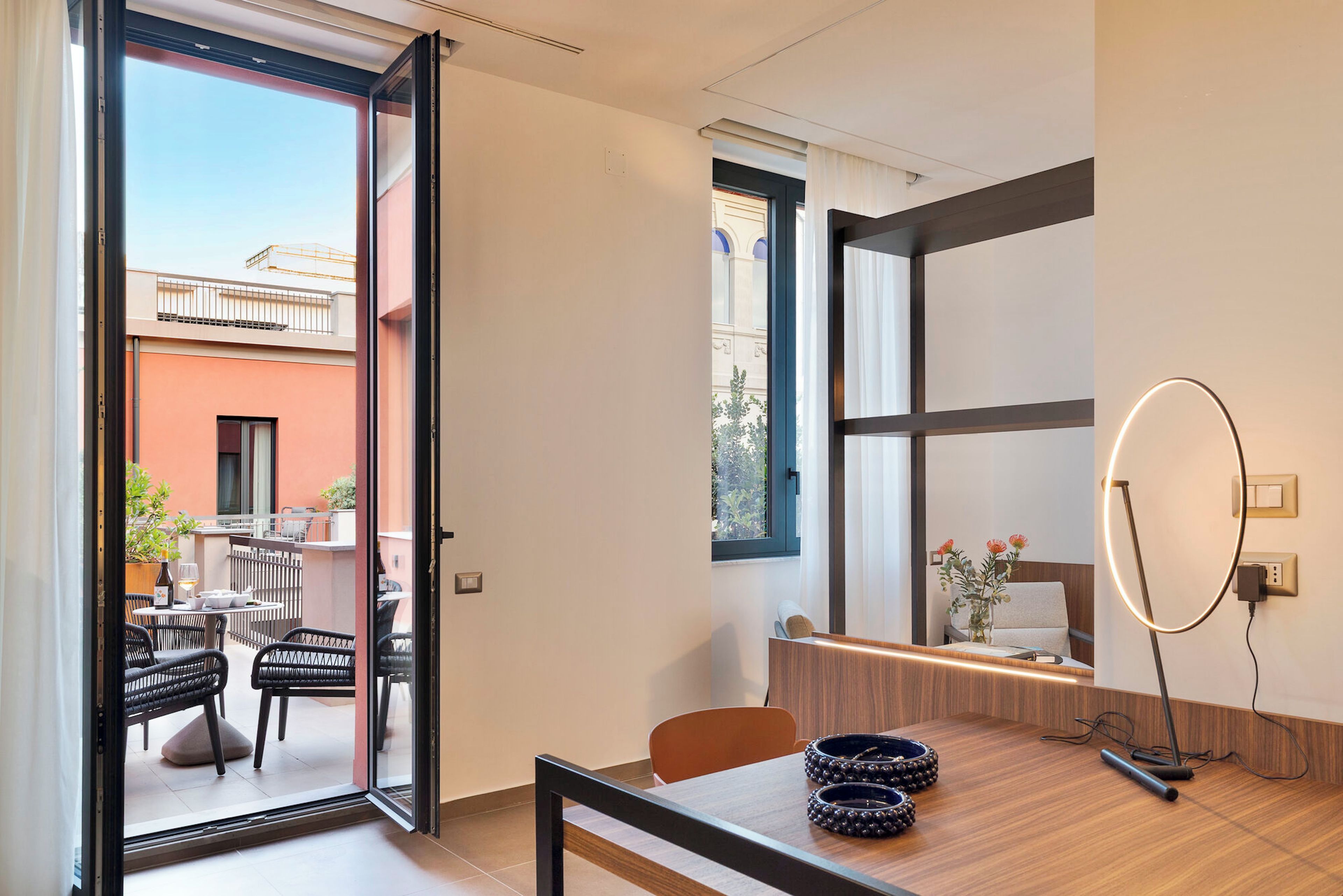 Um interior moderno com área de refeições, vista para a varanda externa e um espelho grande.