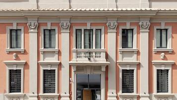 Fachada de edifício com várias janelas, entrada central e molduras decorativas.
