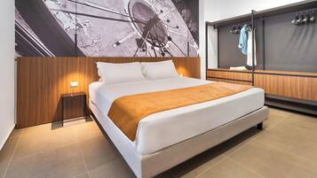 Quarto de hotel moderno com uma cama grande, uma mesa de cabeceira, um painel de cabeceira de madeira e uma TV fixada na parede.