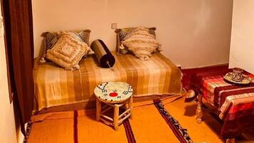 Quarto aconchegante com cama, uma mesinha e luminária pendente.