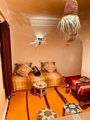 Quarto aconchegante com cama, uma mesinha e luminária pendente.