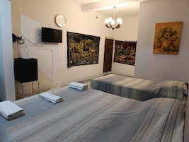 Quarto de hotel com duas camas, televisão de tela plana, obras de arte nas paredes e um lustre.