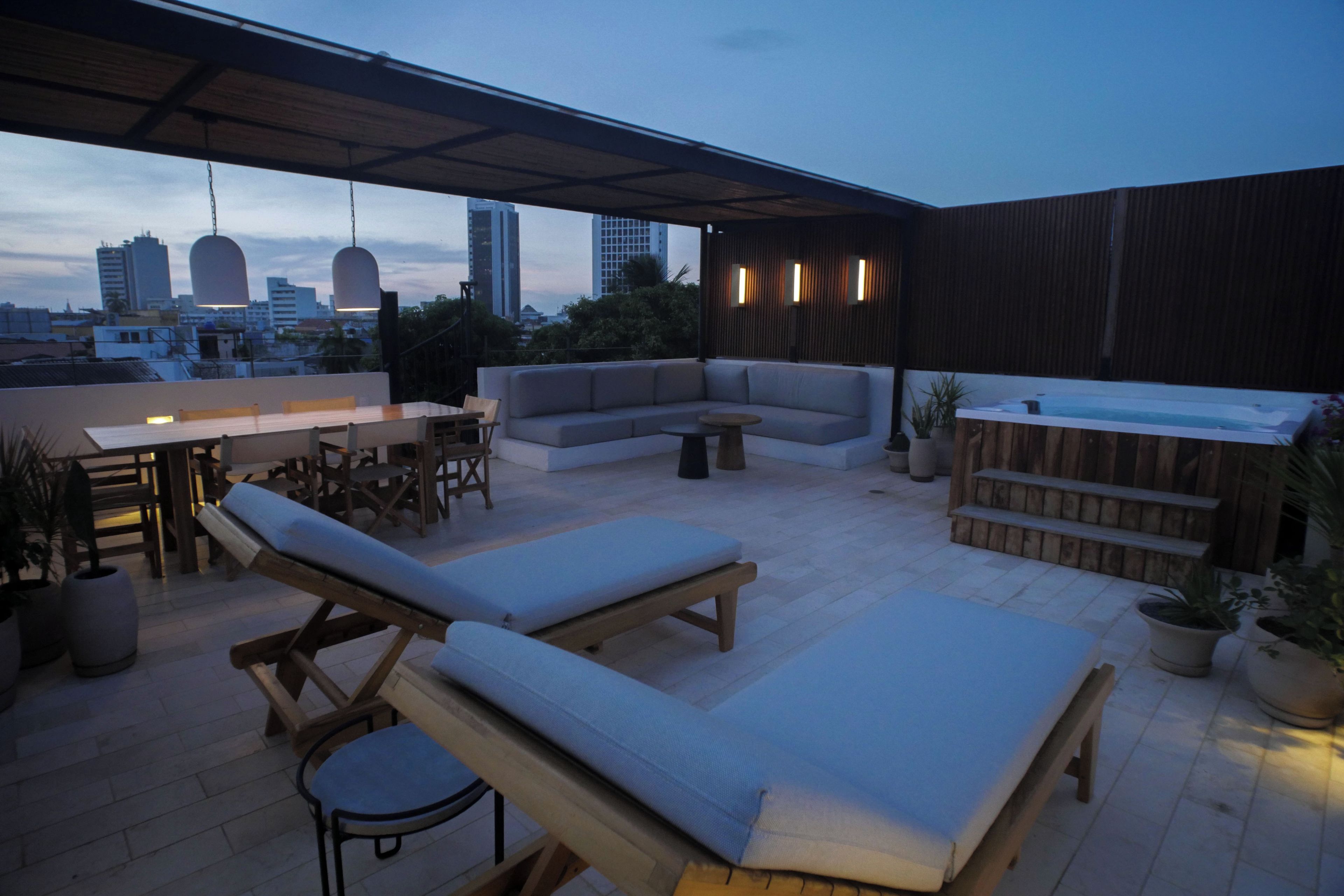 Um pátio externo com mesa de jantar, cadeiras de lounge, um sofá e uma banheira de hidromassagem.