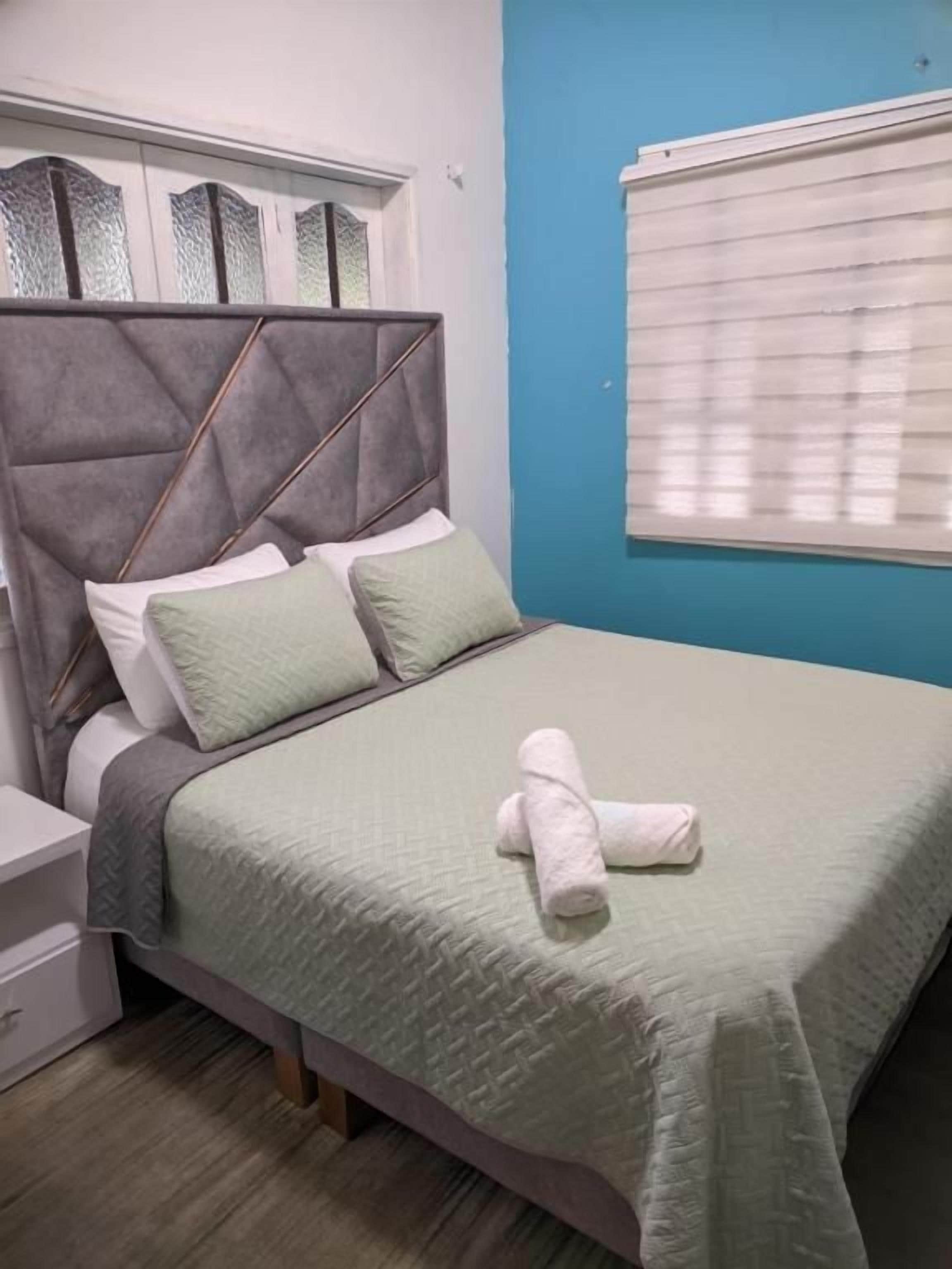 Cama com cabeceira, travesseiros e cobertor.