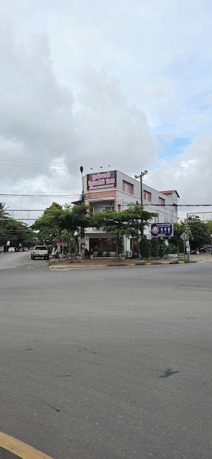 Um edifício com uma placa indicando 'KHMER HOUSE KAMPOT' e outra placa para 'Partido do Povo Cambojano'.