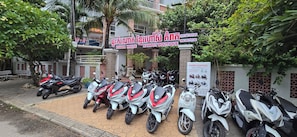Um edifício com uma placa indicando 'Khem House Boutique' e uma placa de aluguel de scooters.