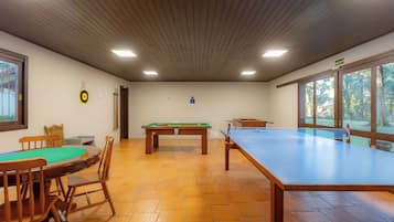 Um quarto com mesa de bilhar, mesa de sinuca e mesa de pingue-pongue.