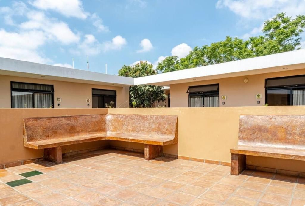 Pátio com duas bancas, piso de azulejos e um edifício com janelas e porta.