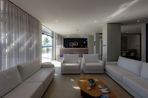 Um hall de hotel moderno com balcão de recepção, área de estar e vista para o exterior.