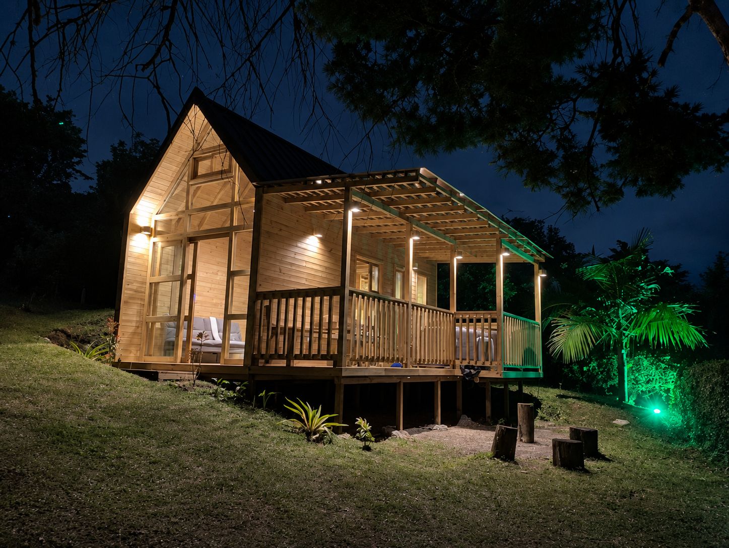 Uma cabana de madeira com varanda, janelas amplas e um jardim iluminado.