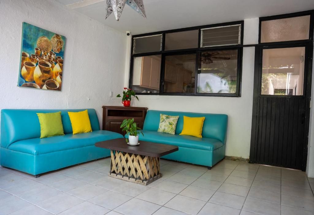 Uma sala de estar com um sofá azul, uma mesa de centro de madeira e um quadro na parede.