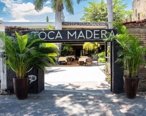 A entrada do Hotel Tocamadera, com área de estar externa e plantas em vasos.