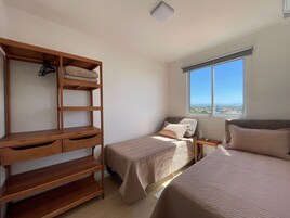 Quarto com beliche, estante de madeira e janela com vista para a cidade.