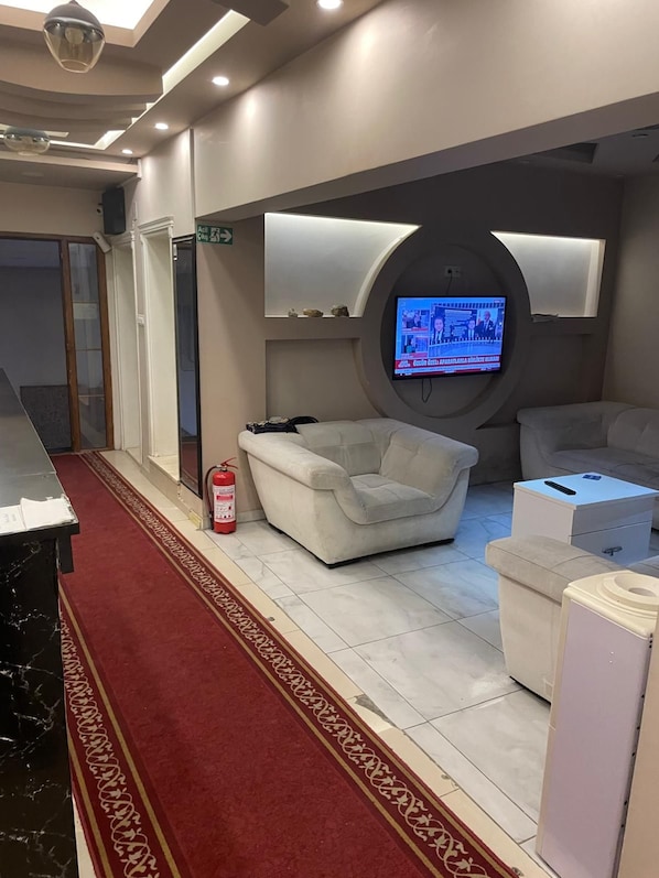 Quarto moderno com televisão de tela plana na parede, um sofá, uma mesinha e um tapete vermelho.