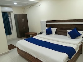 Quarto de hotel com uma cama grande, guarda-roupa de madeira, mesa de cabeceira e ar condicionado fixado na parede.